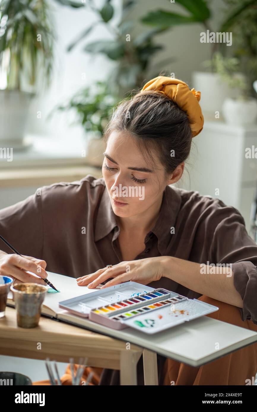 Creative woman artist painting on paper of sketchbook with watercolour ...