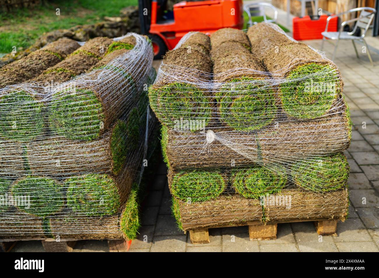 Stacked rolls of sod secured with mesh netting on pallets, ready for ...