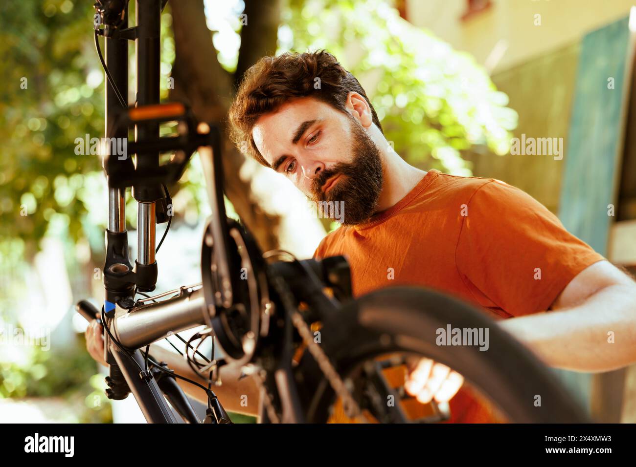 Focused young man thoroughly examining his bike tire for rubber damages ...