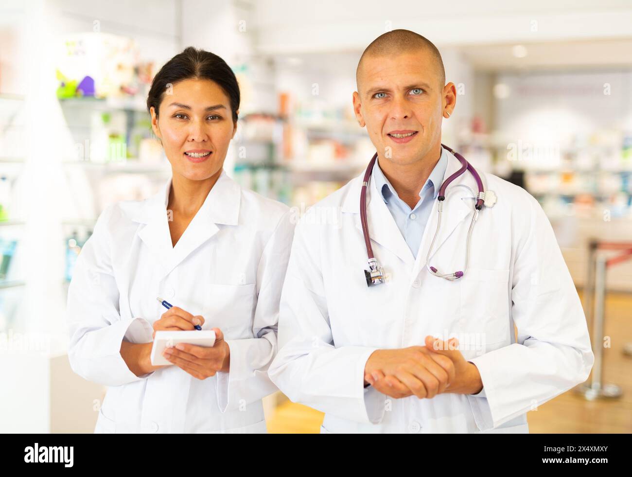 Portrait of two pharmacists - men and women in white coats in pharmacy ...
