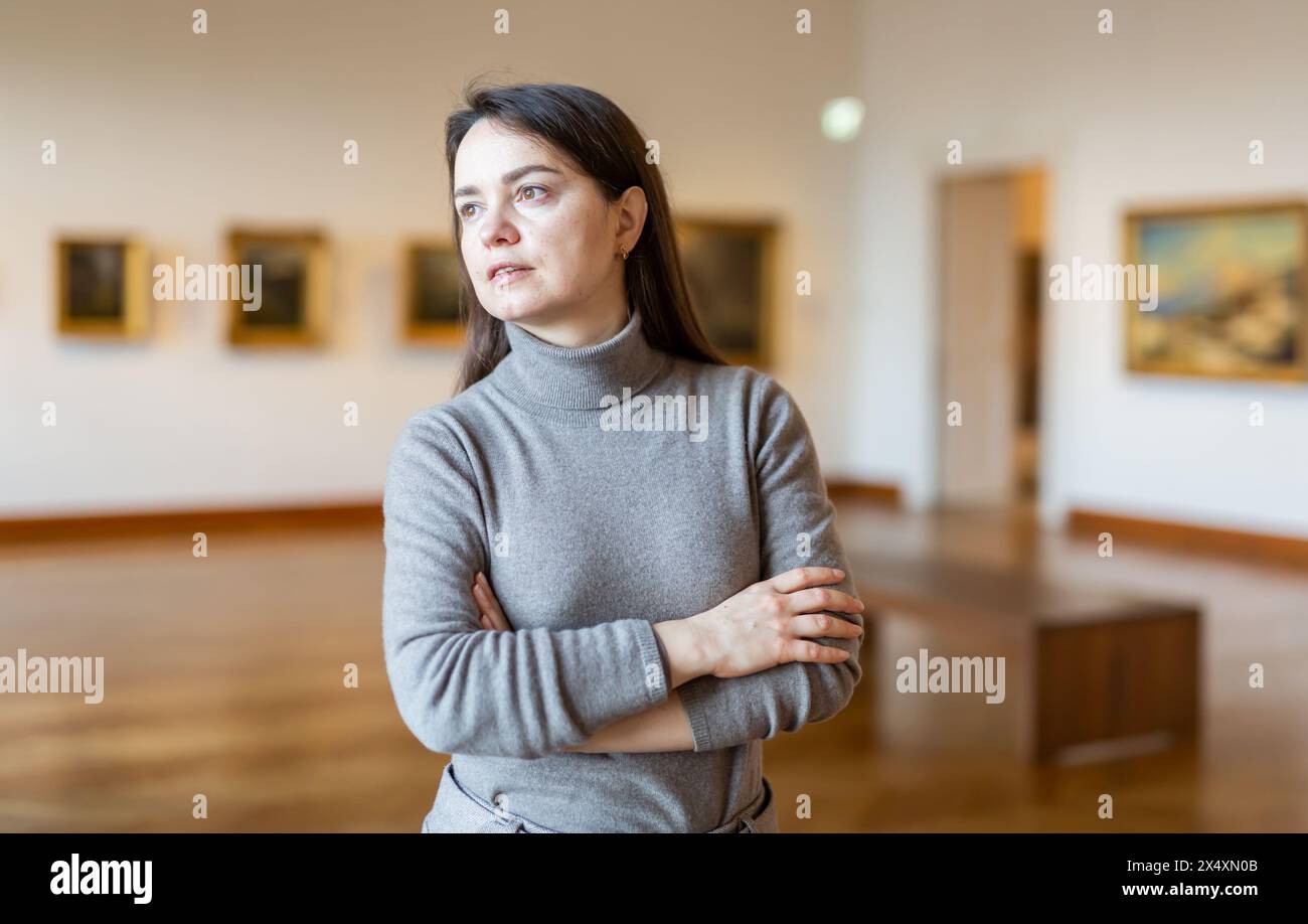 Interested woman visiting exhibition of paintings in art museum Stock ...