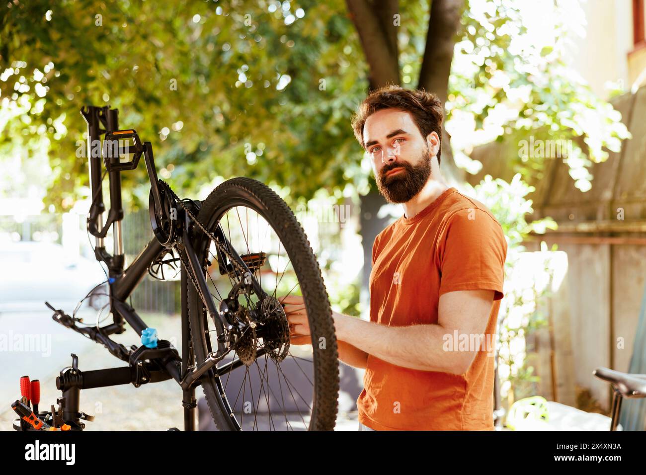 Portrait shot of committed healthy male cyclist holding damaged bicycle ...
