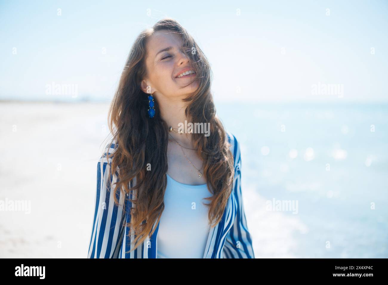 happy stylish 40 years old woman on the seacoast enjoying peace of mind ...