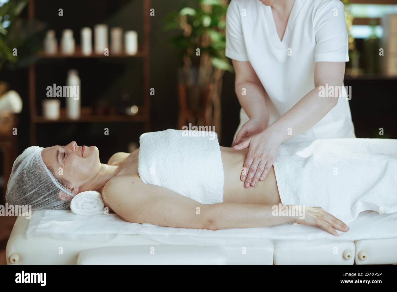 Healthcare time. massage therapist in massage cabinet massaging clients belly on massage table ...