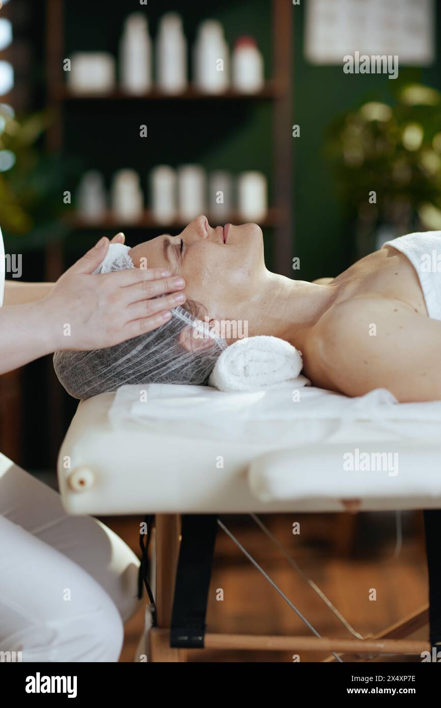 Healthcare time. medical massage therapist in massage cabinet massaging clients face on massage ...