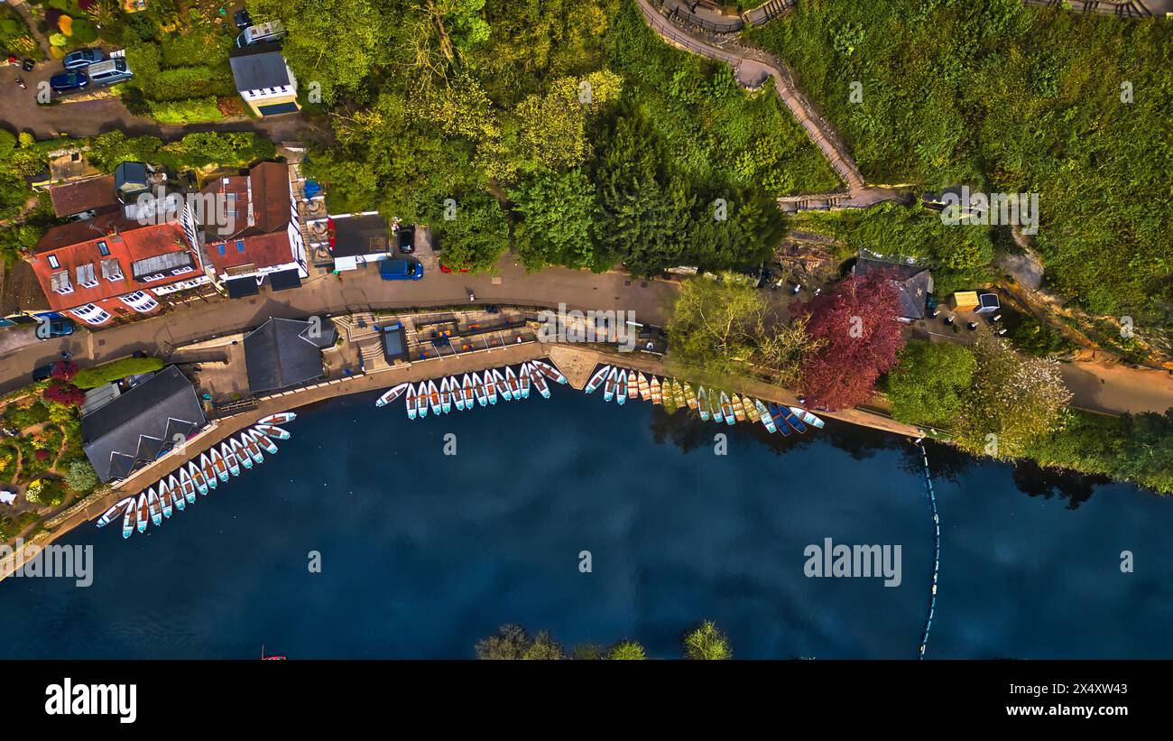 Aerial view of a lakeside with aligned boats, surrounded by lush ...