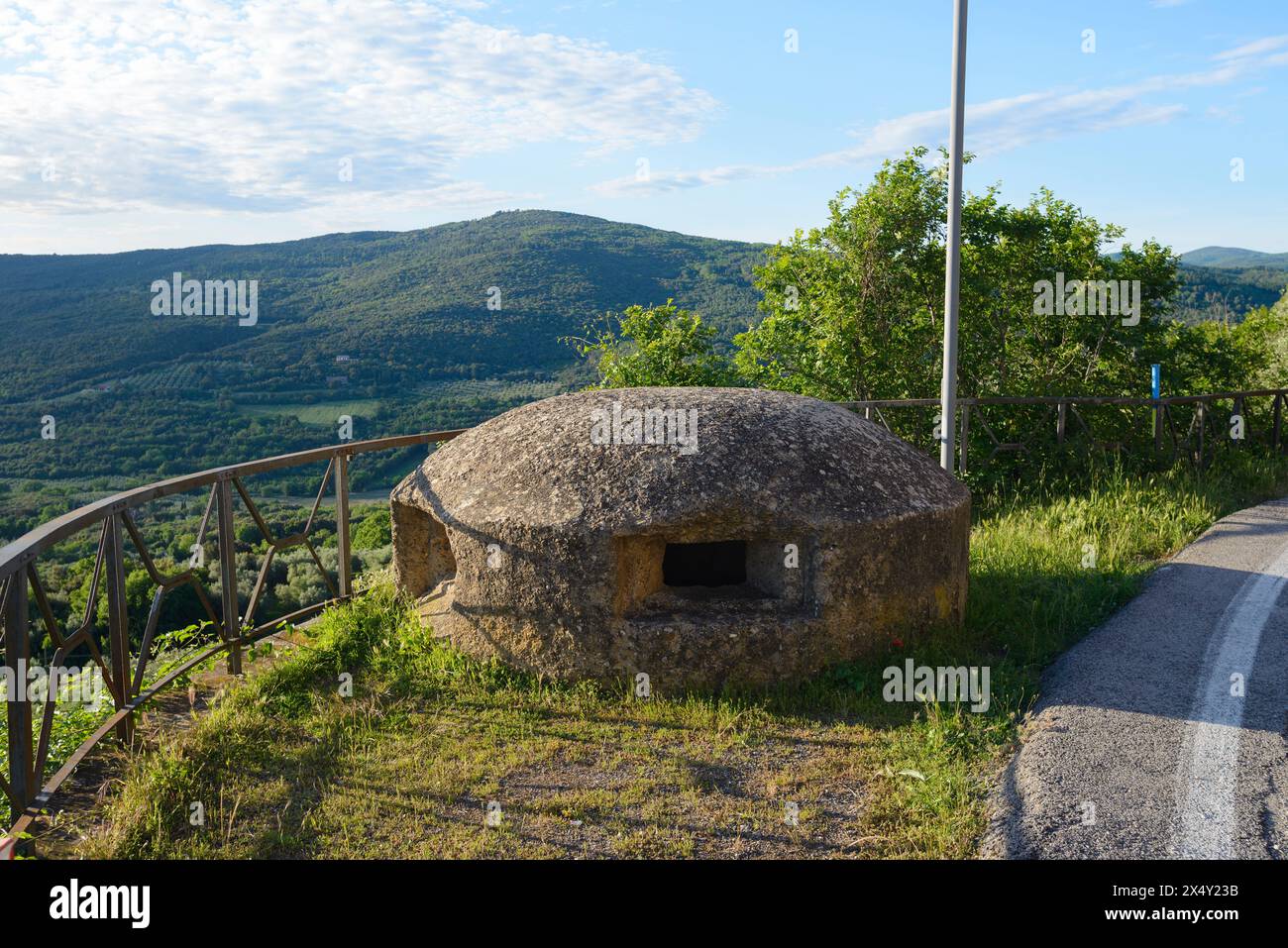An old concrete fort from World War II. Road, overlooking green hills ...
