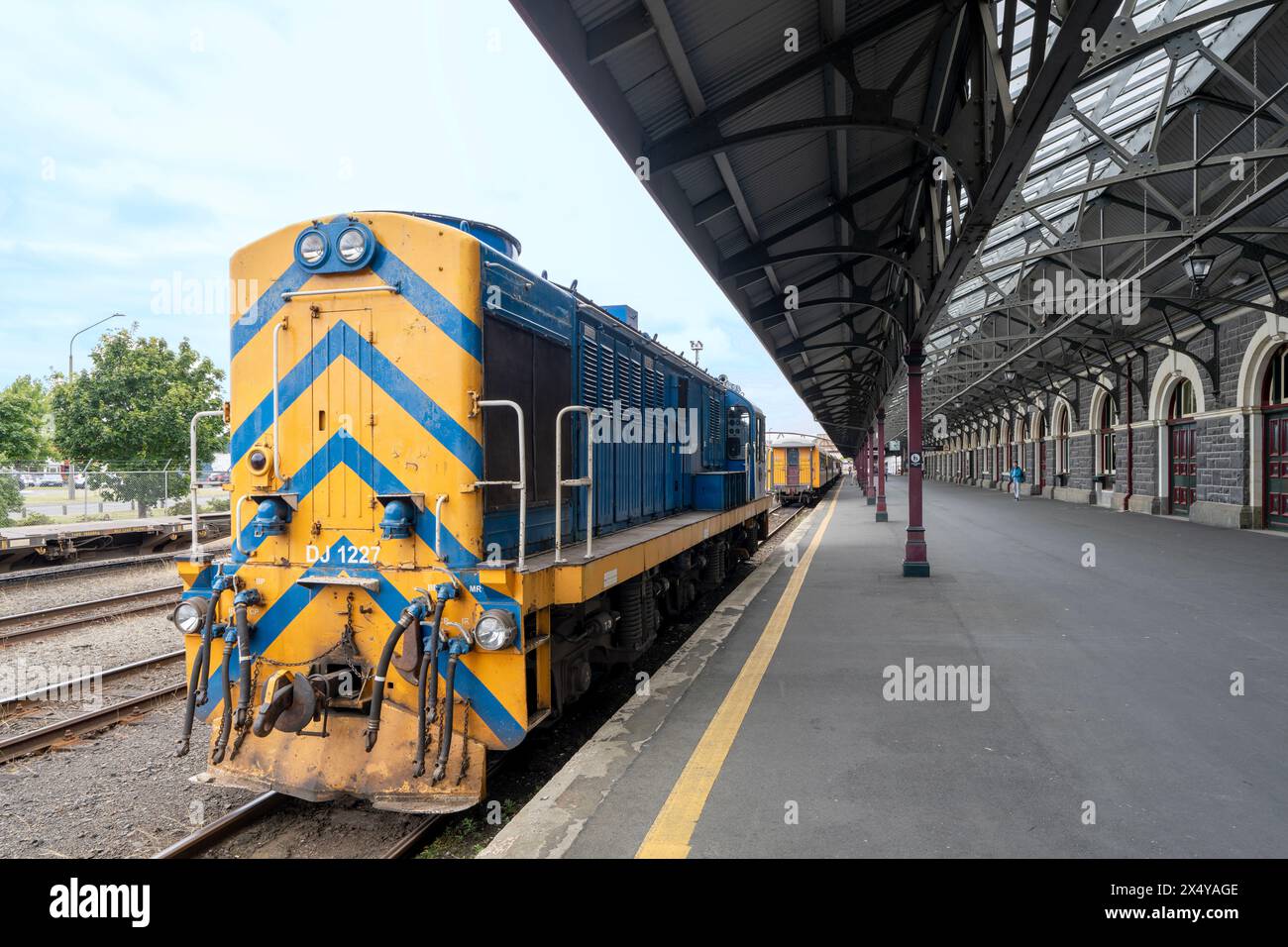 A blue and yellow locomotive, DJ 1227, stationed under the iconic ...