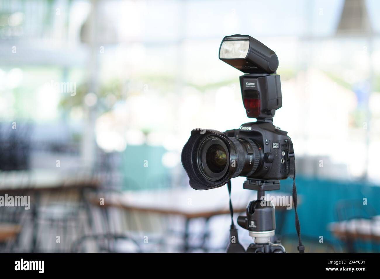 Black Canon DSLR camera mounted on a tripod with an external flash ...
