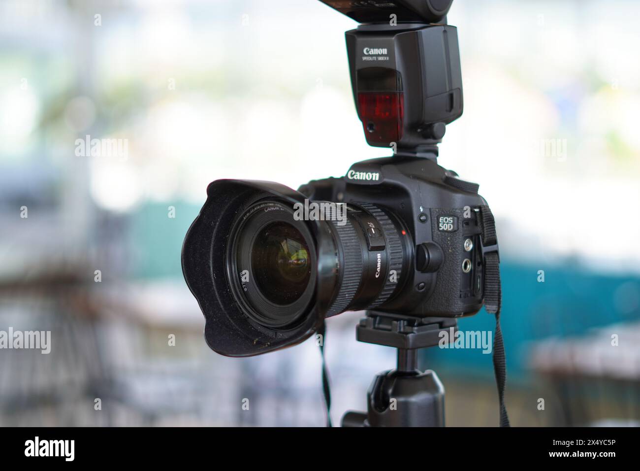 Black Canon DSLR camera mounted on a tripod with an external flash ...
