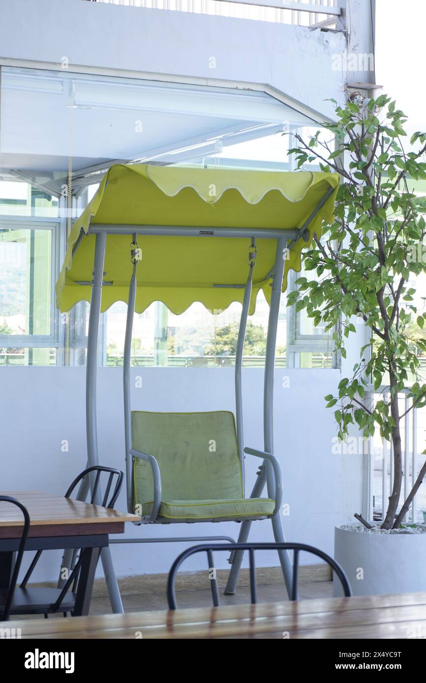 A modern swing chair with a fabric roof that is used for relaxing and ...