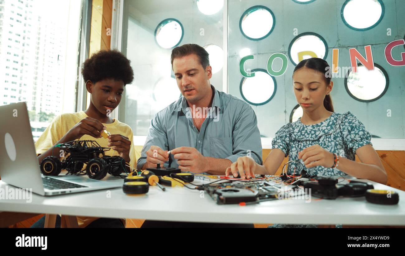 Skilled teacher teaching diverse students fixing car model by using ...