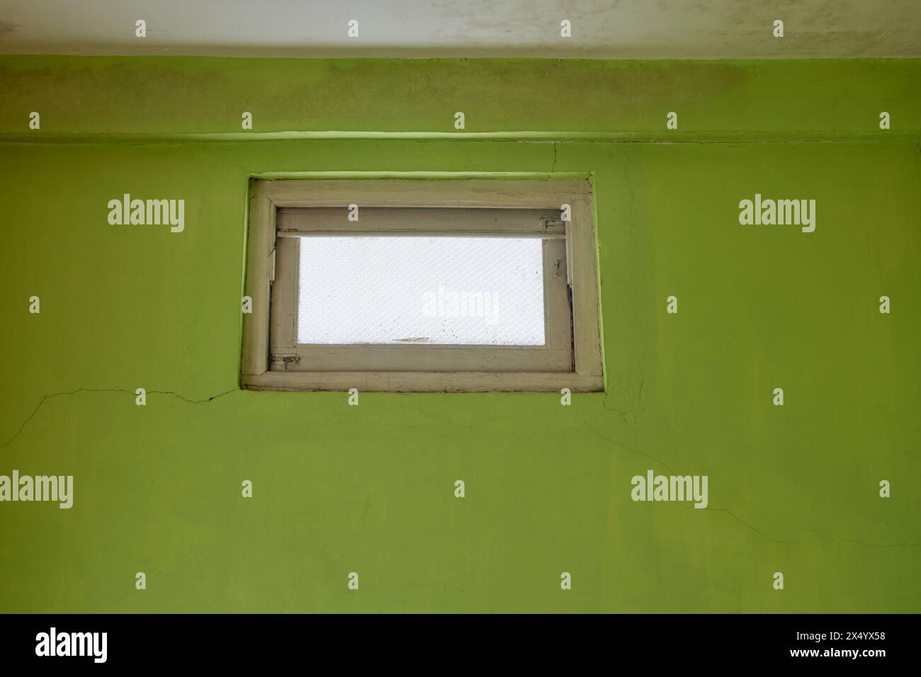 green cracked wall with small glass window to allow natural light to ...