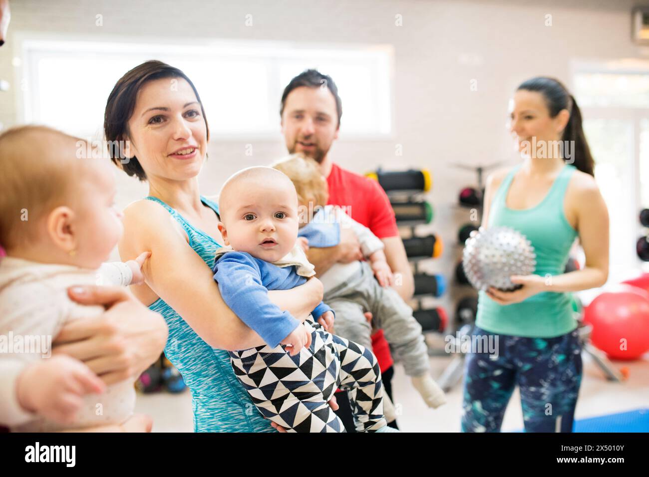 Group exercise class, parents working out with baby in gym. Moms and ...