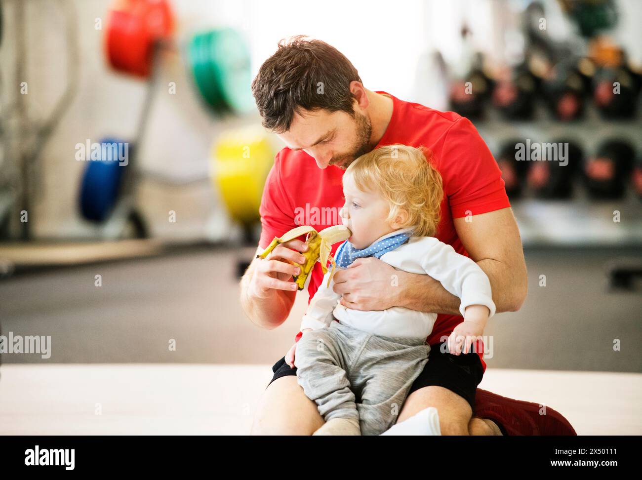 Portrait of new dad on group exercise class in gym, feeding baby with ...