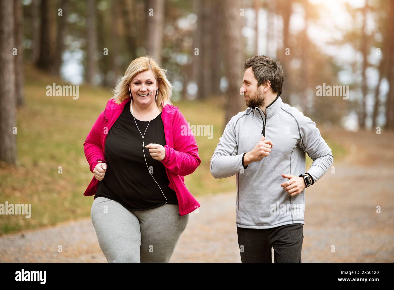 An overweight woman running in nature with friend. Exercising outdoors ...