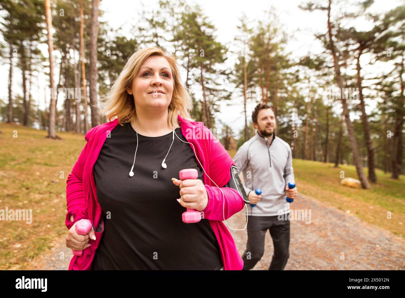 An overweight woman running in nature with friend. Exercising outdoors ...