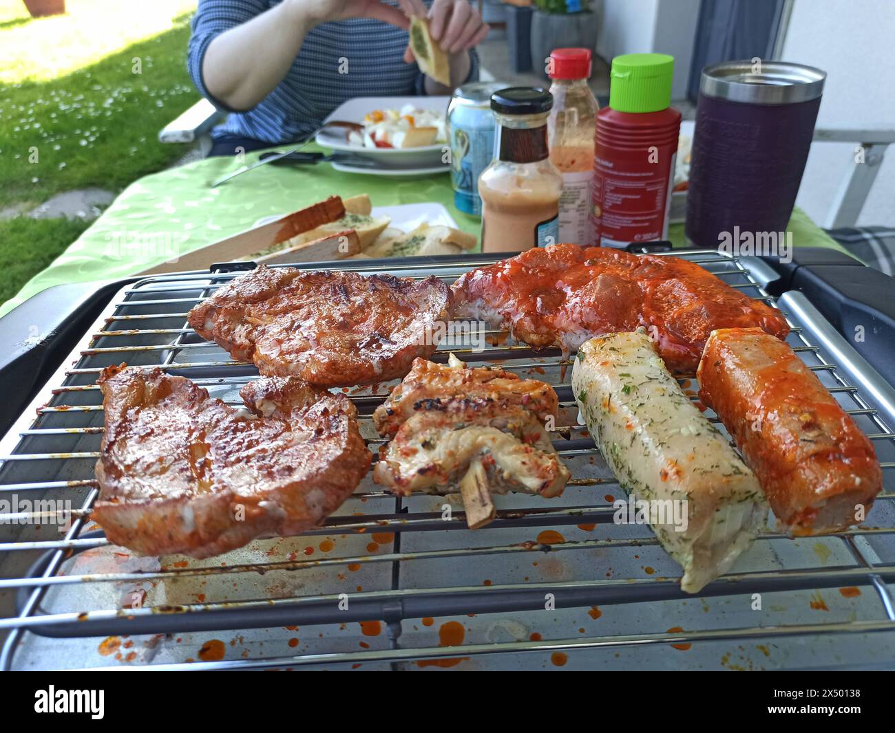 Grillgut auf einem Tischgrill im eigenen Garten. Grillsaison 2024 ...