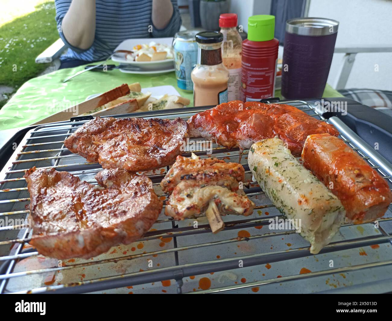 Grillgut auf einem Tischgrill im eigenen Garten. Grillsaison 2024 *** Barbecue food on a table ...