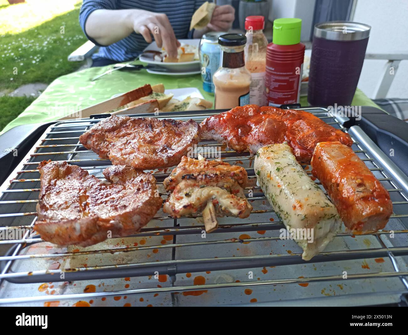 Grillgut auf einem Tischgrill im eigenen Garten. Grillsaison 2024 ...