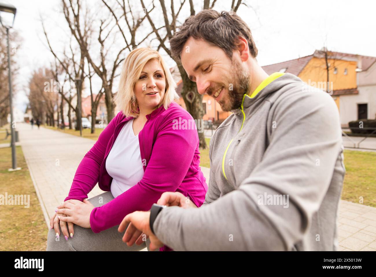 Overweight woman resting after run, personal trainer checking her ...