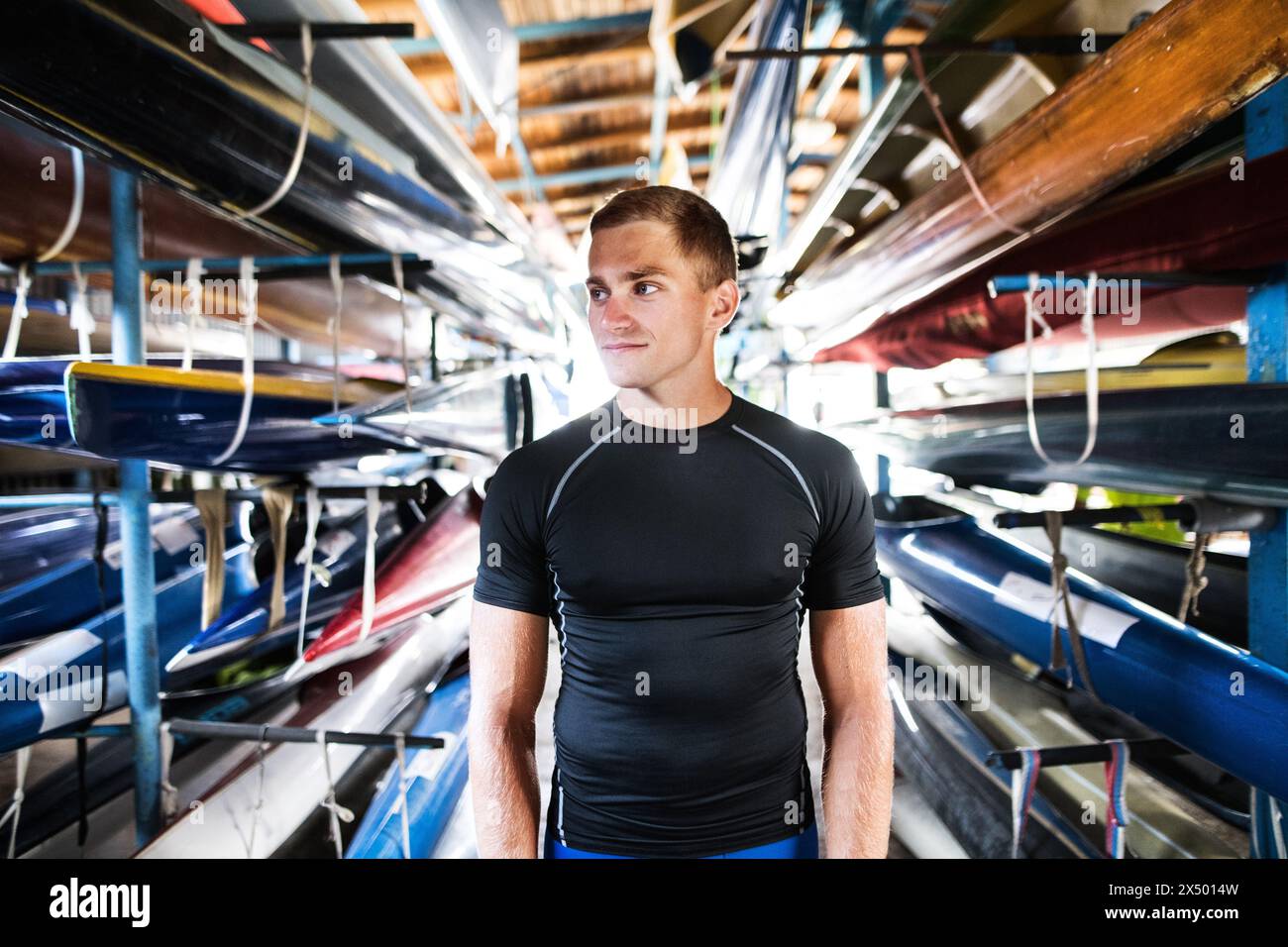 Portrat of young canoeist standing in the middle of stacked canoes ...