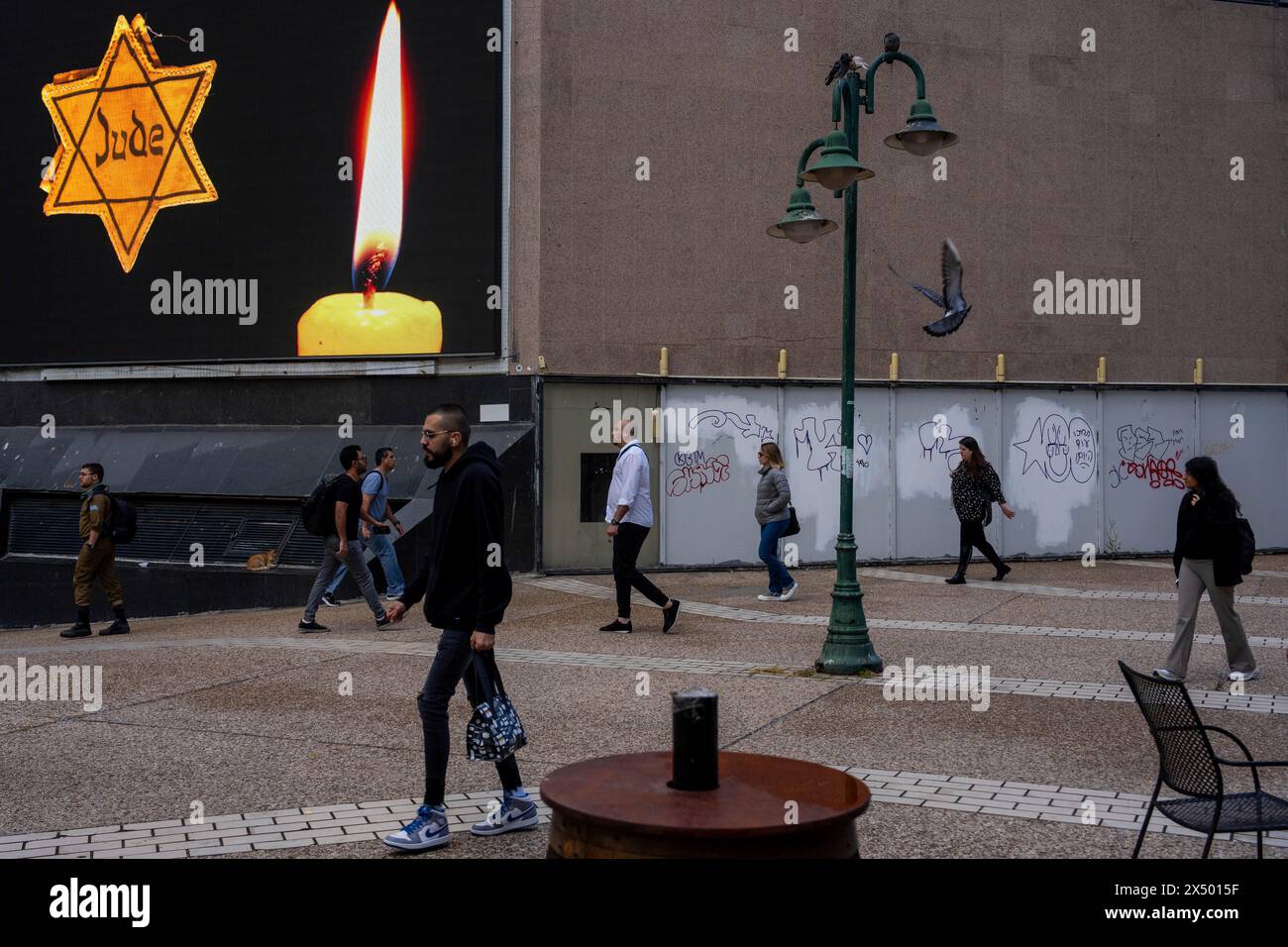 People walk next to a billboard showing a yellow Star of David that ...