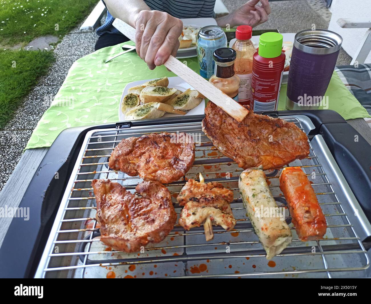 Grillgut auf einem Tischgrill im eigenen Garten. Grillsaison 2024 ...