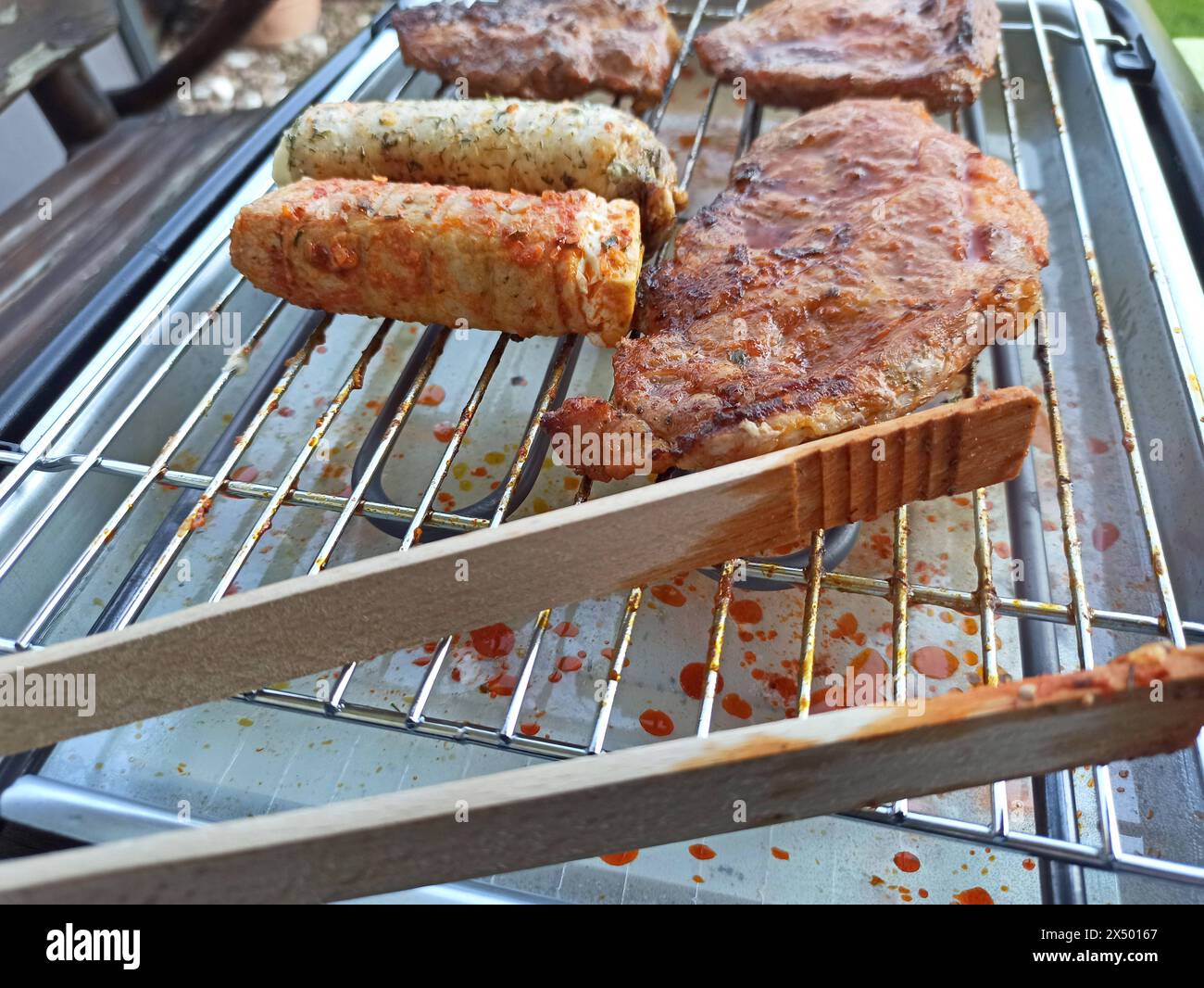 Grillgut auf einem Tischgrill im eigenen Garten. Grillsaison 2024 ...