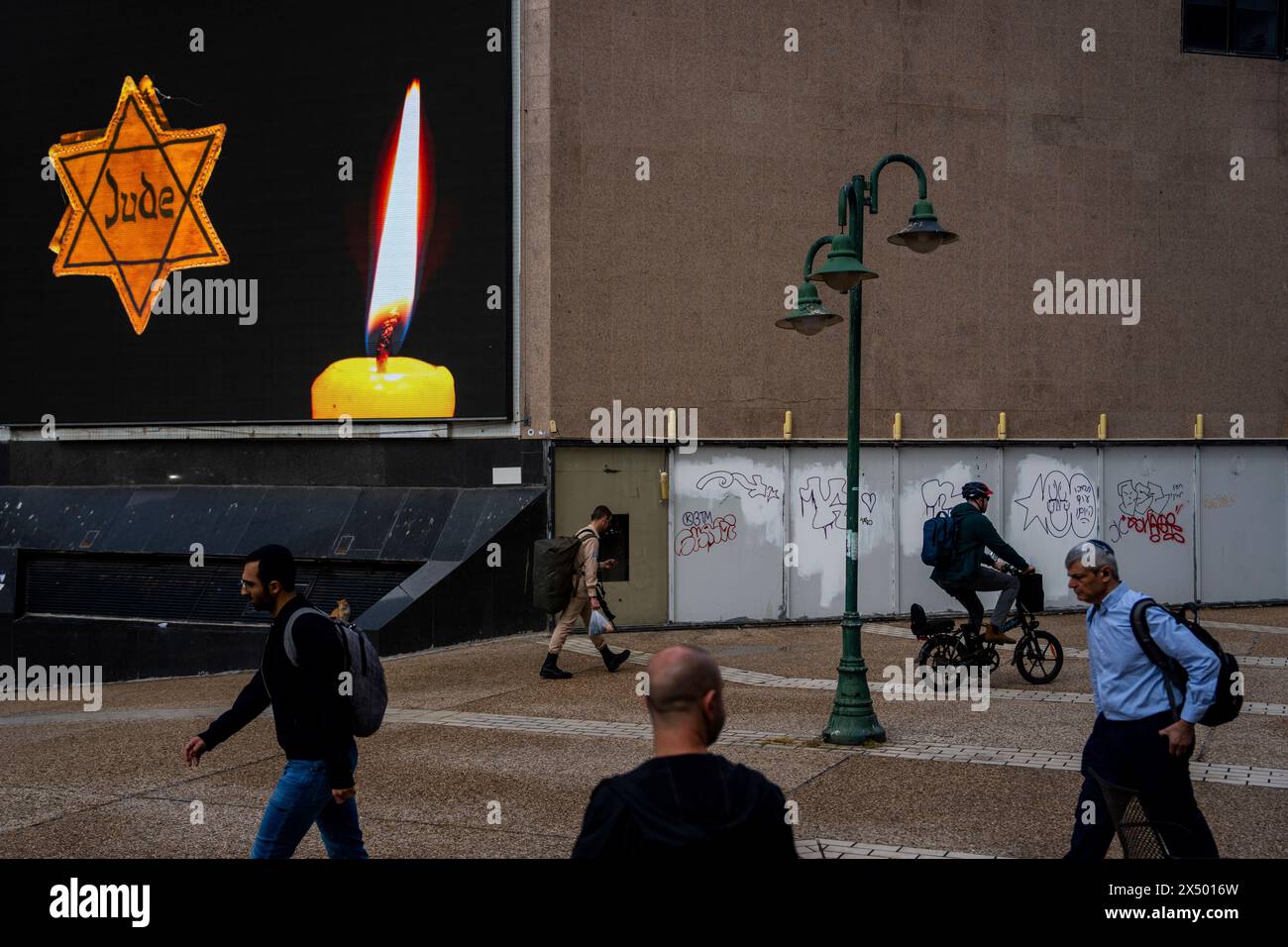 People walk next to a billboard showing a yellow Star of David that ...