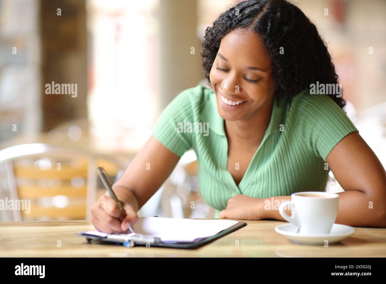 Happy black woman filling form in a restaurant terrace Stock Photo - Alamy
