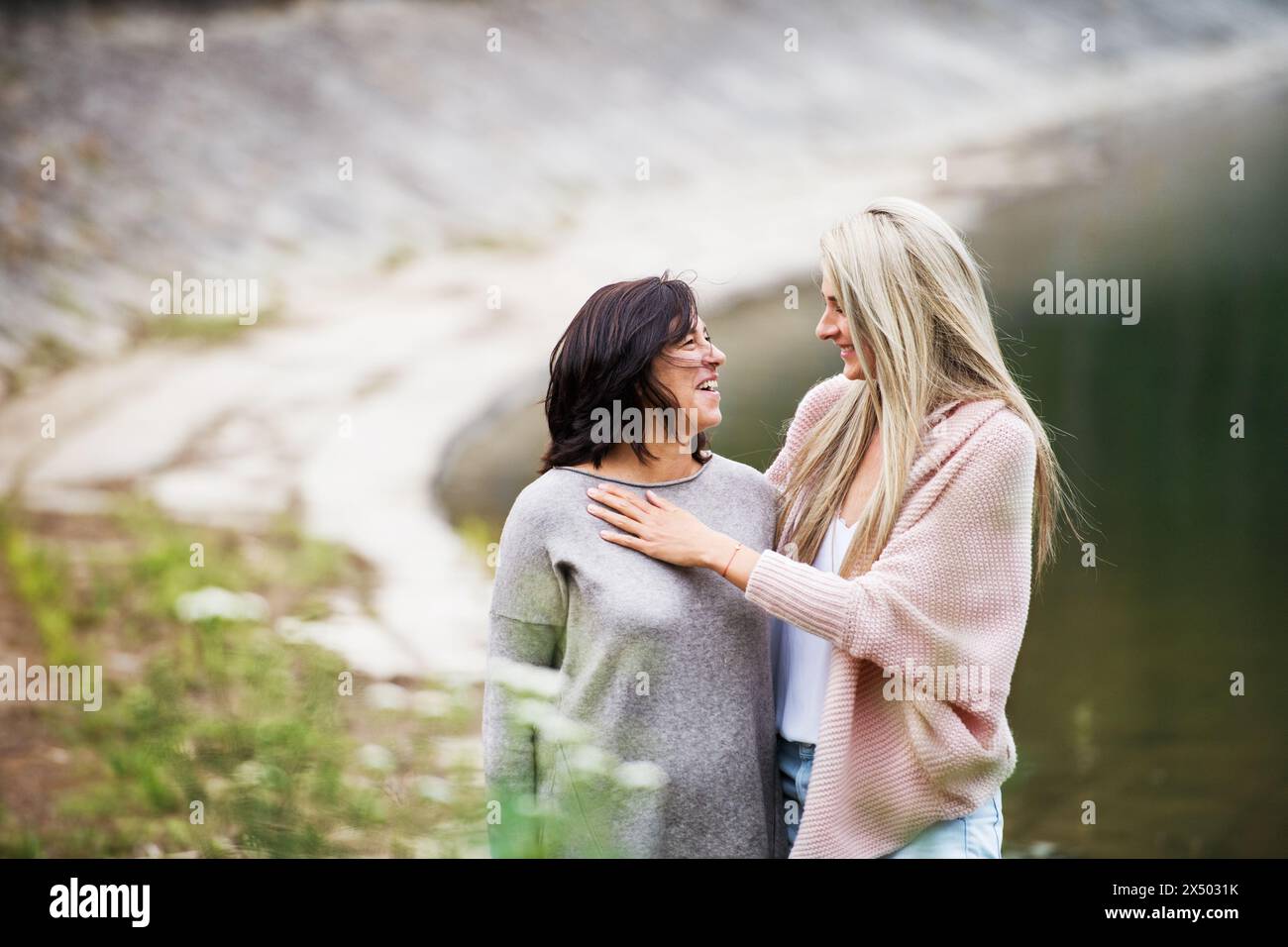 Adult daughter spending time with her mother. Mom and daughter outdoors, on walk by reservoir ...