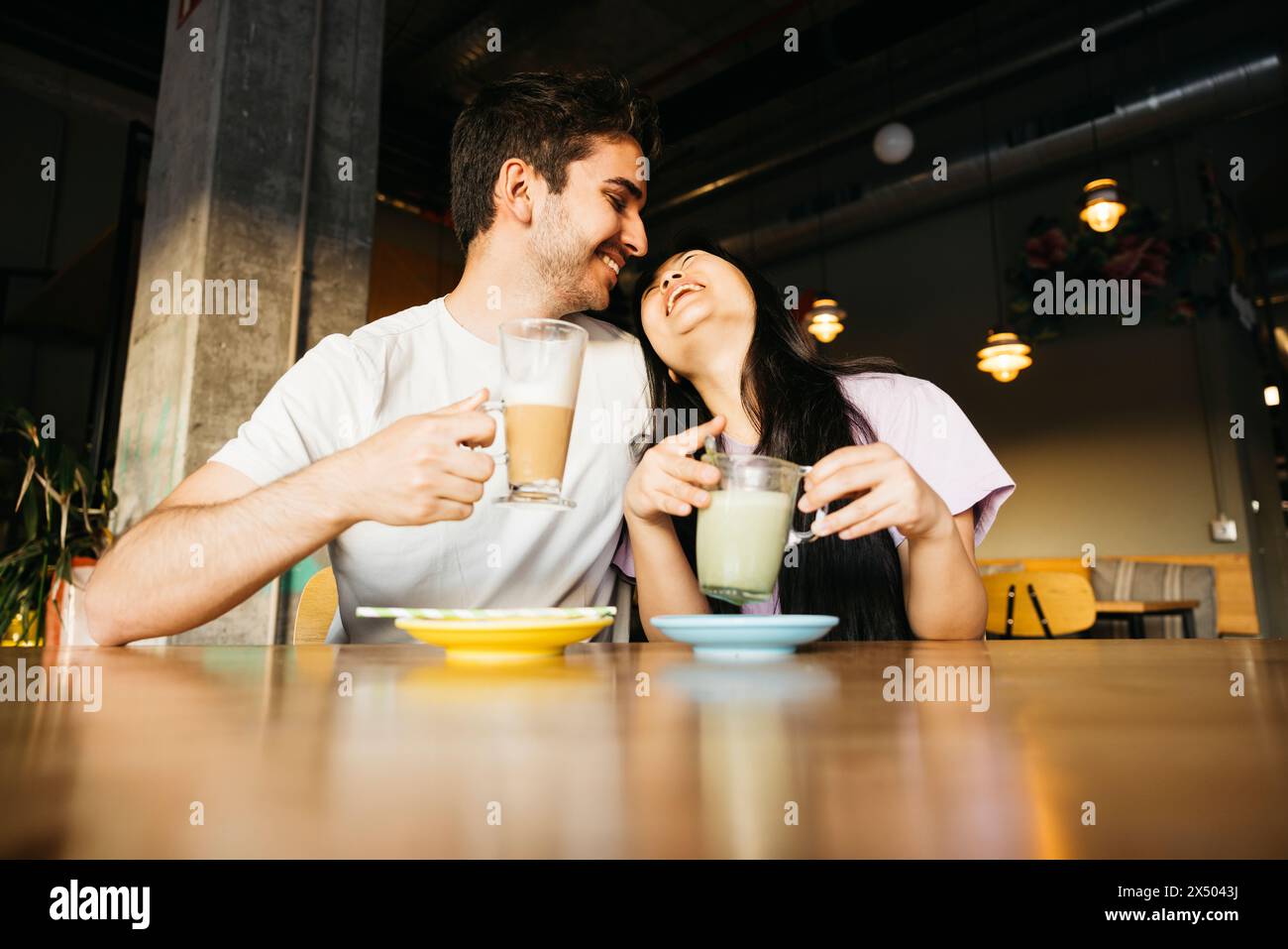 Young smiling couple sitting inside a cafe. Couple on a date at a local ...