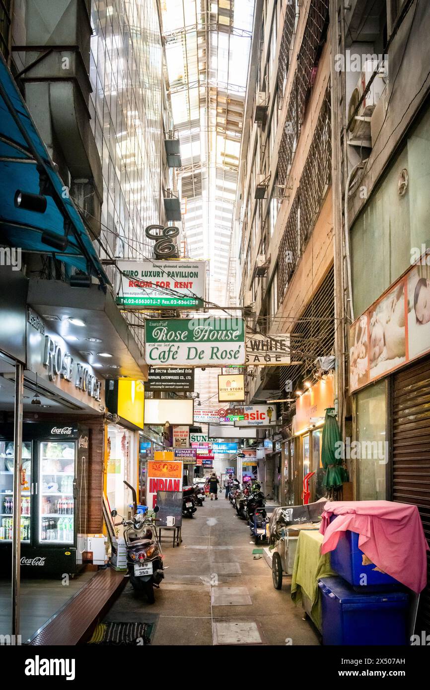 Looking down a tight packed alley with small shops, markets stalls and ...
