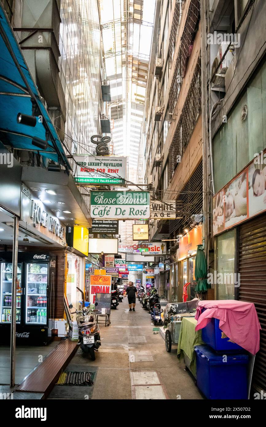 Looking down a tight packed alley with small shops, markets stalls and ...