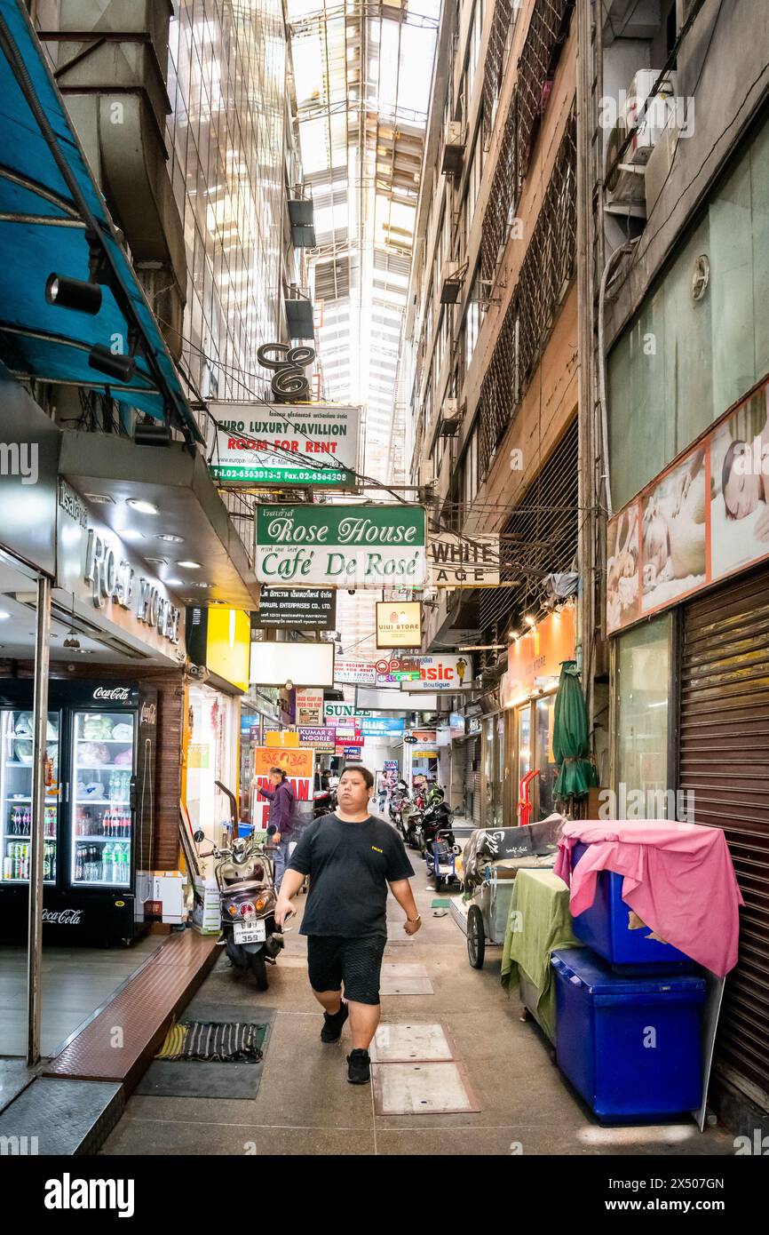 Looking down a tight packed alley with small shops, markets stalls and ...