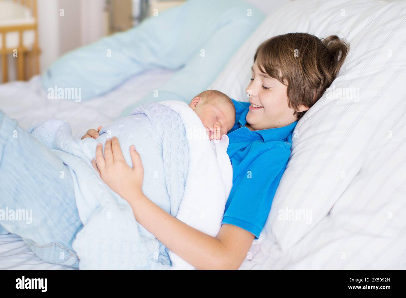 Siblings meet newborn baby in hospital. Child holding new infant ...