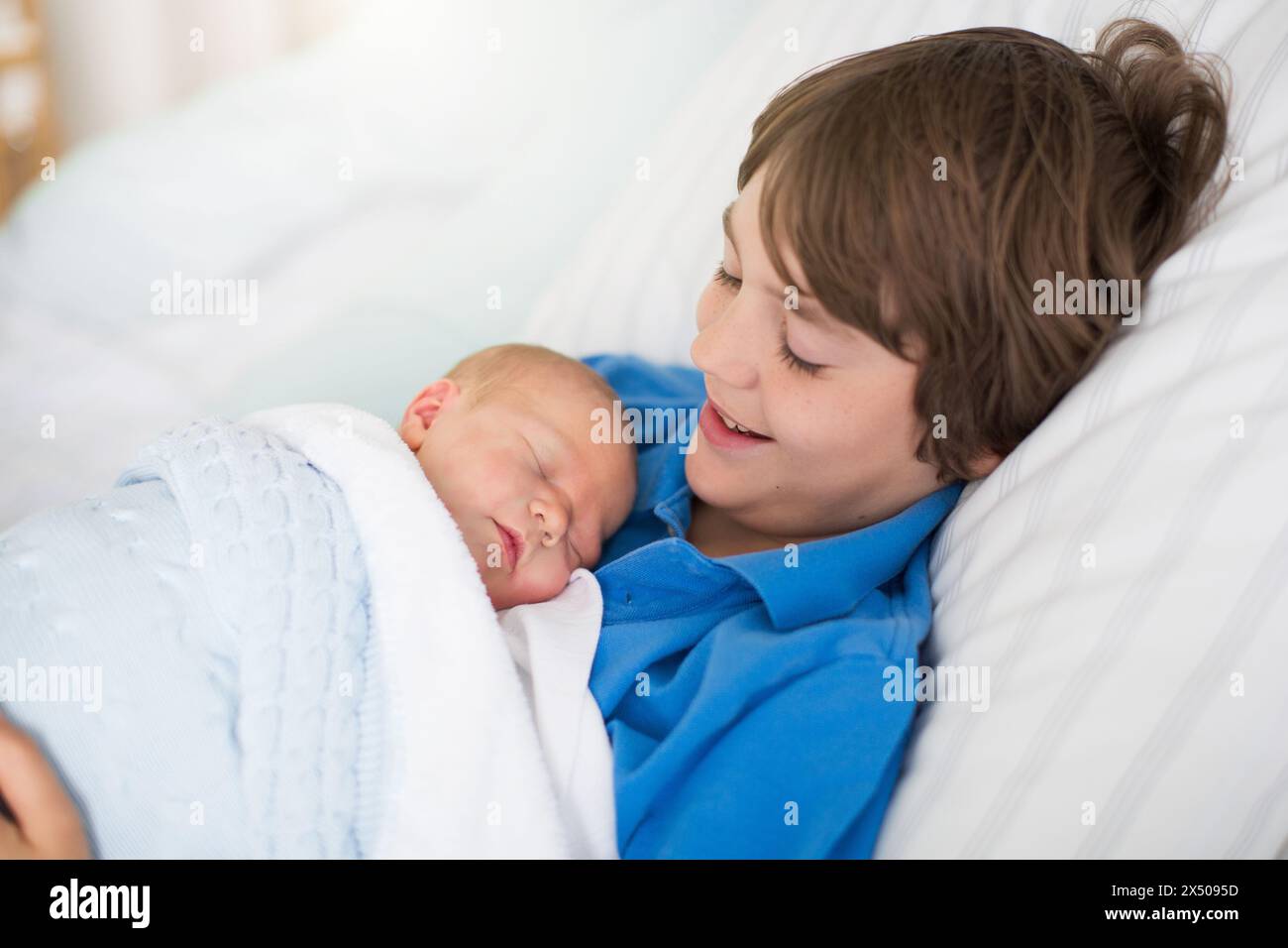 Siblings meet newborn baby in hospital. Child holding new infant ...