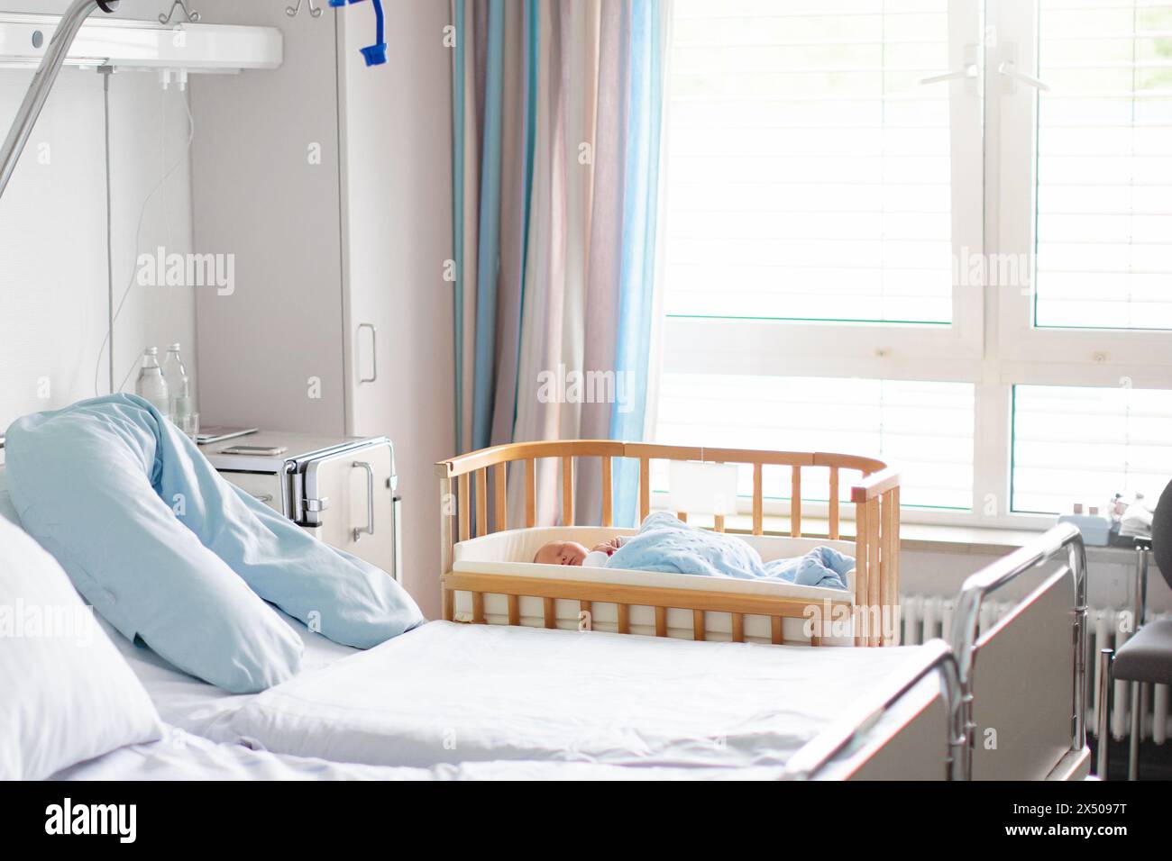 Newborn baby in hospital room. New born child in wooden co-sleeper crib ...