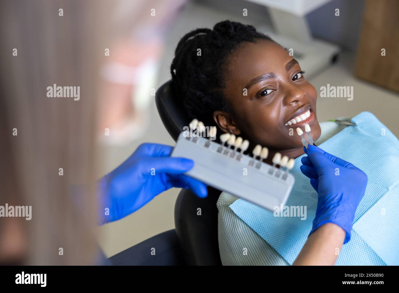Dentist choosing the color for tooth implant for the female patient ...