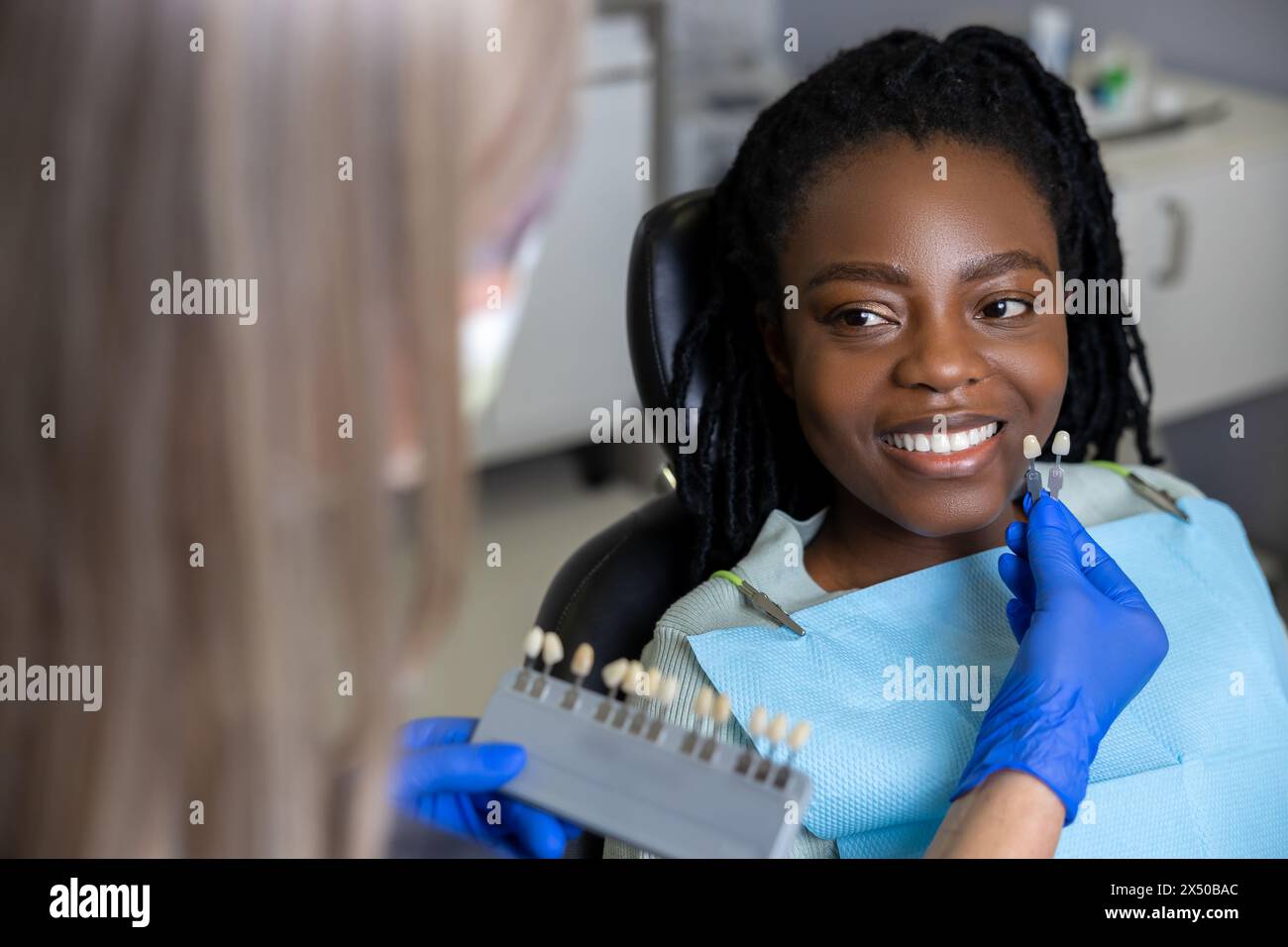 Dentist choosing the color for tooth implant for the female patient ...