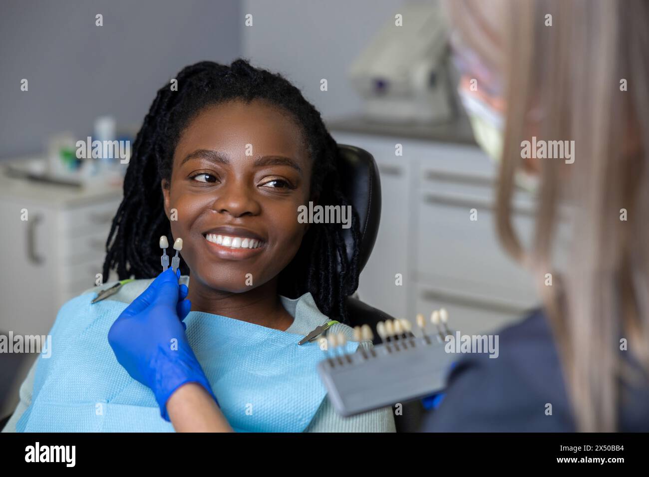 Dentist choosing the color for tooth implant for the female patient ...