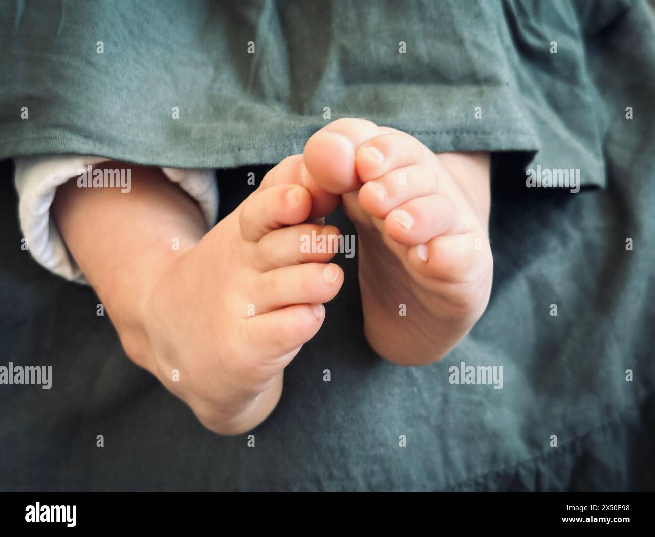Close-up of a barefoot toddler's feet sticking out from under a sheet ...
