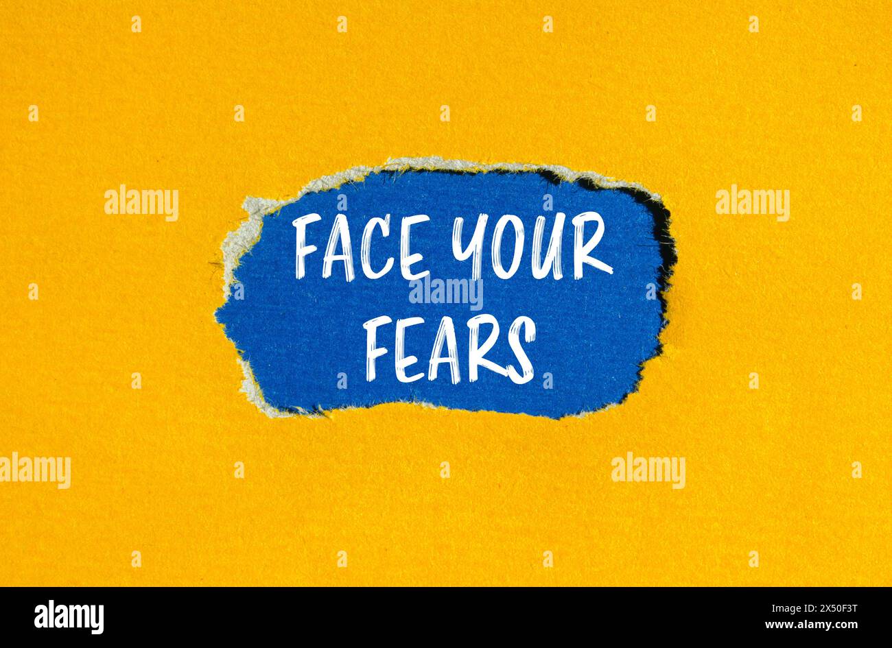 Face your fears words written on ripped yellow paper with blue ...