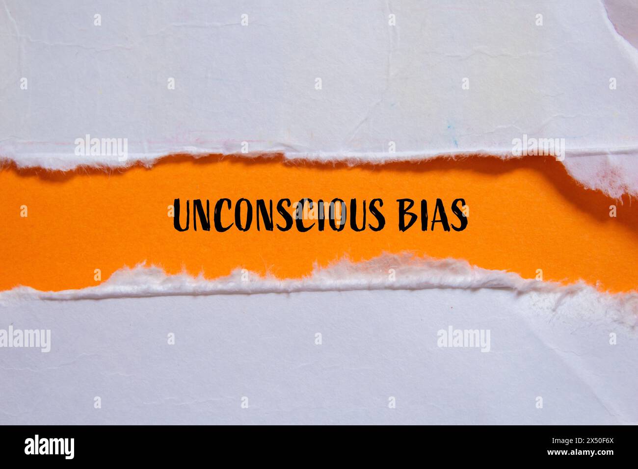 Unconscious bias words written on ripped paper with orange background. Conceptual unconscious ...