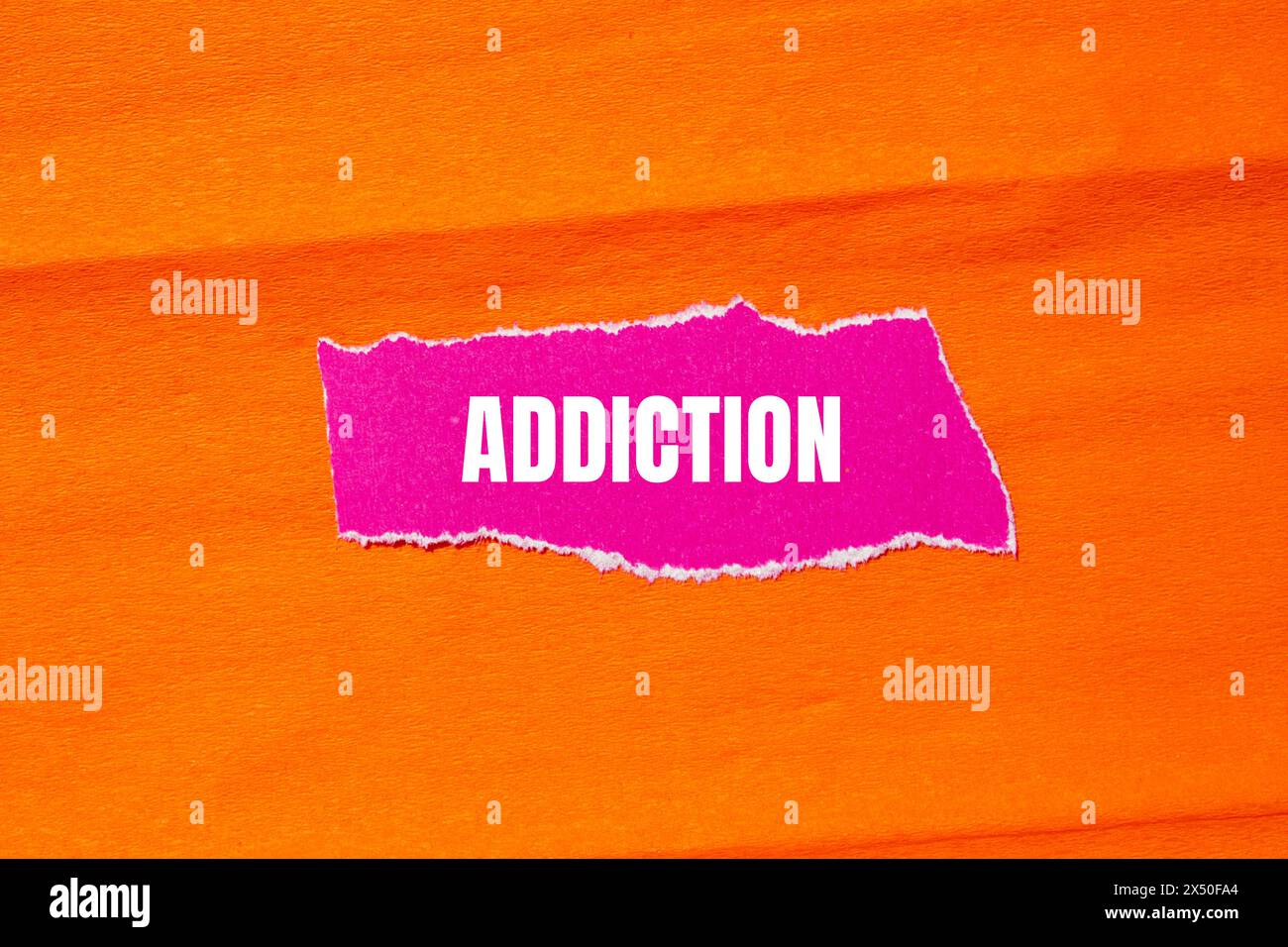 Addiction word written on ripped pink paper piece with orange ...