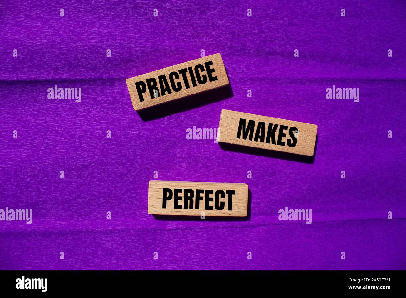 Practice makes perfect words written on wooden blocks with purple ...