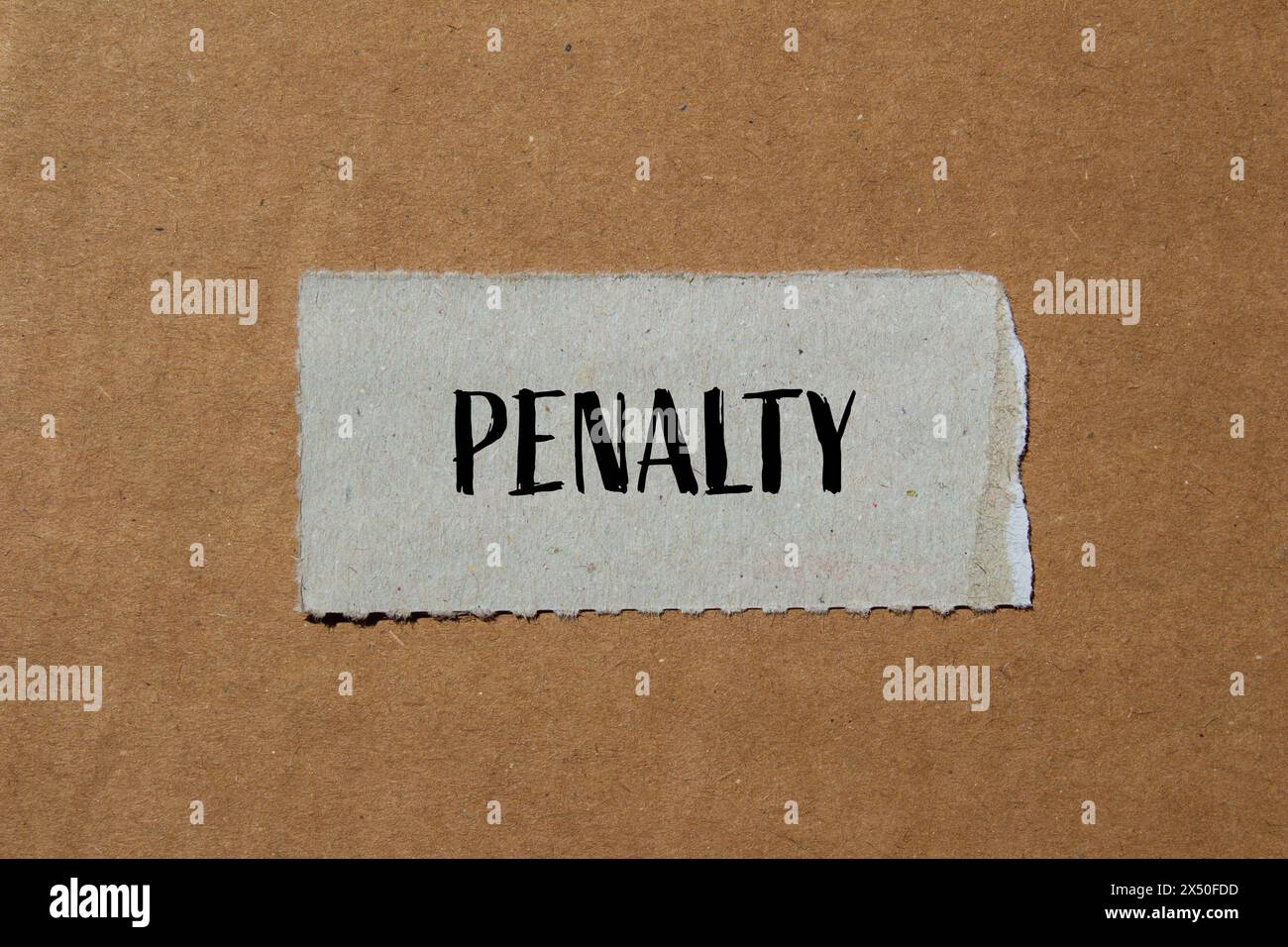 Penalty word written on ripped paper piece with brown background ...