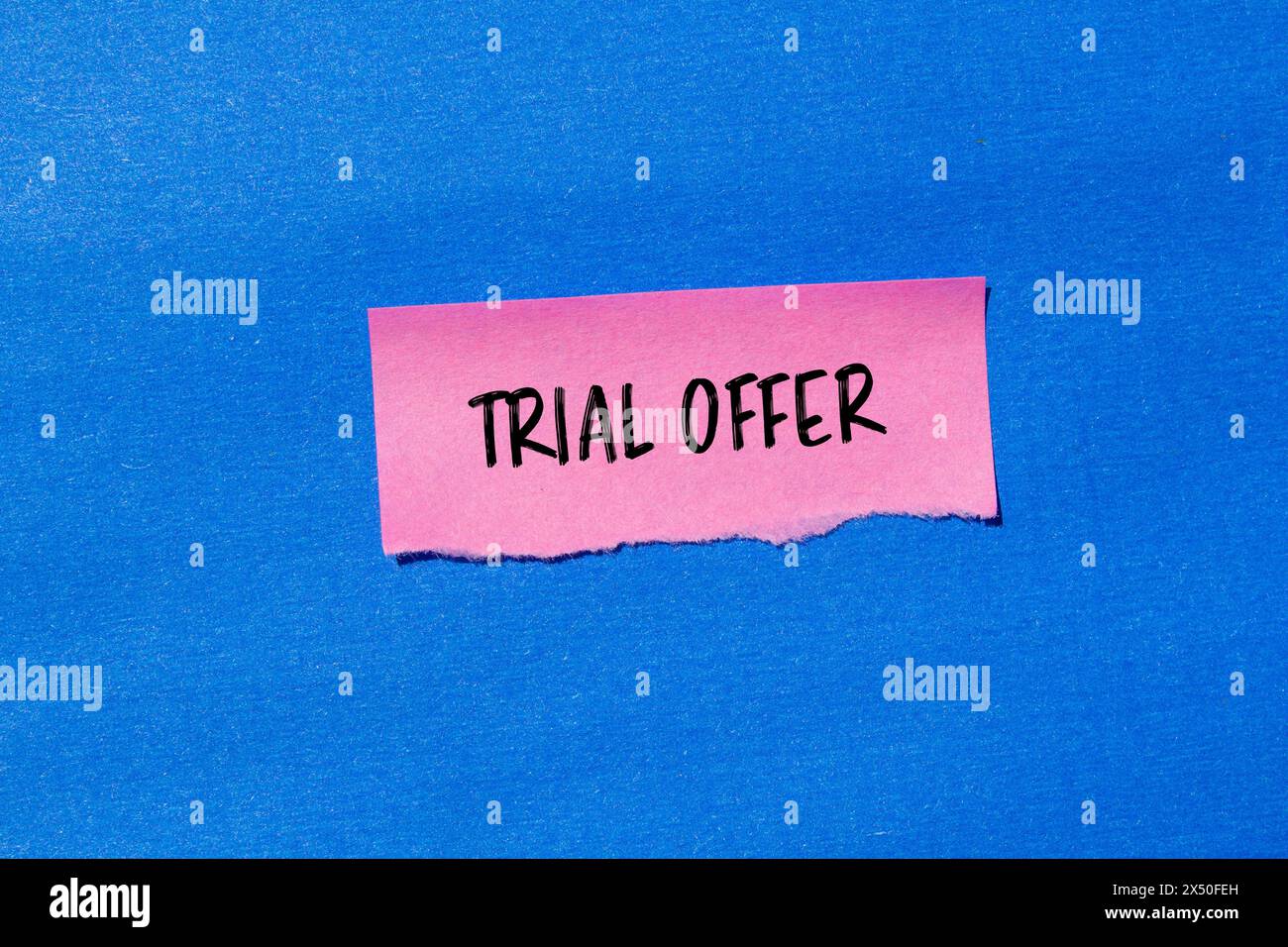 Trial offer words written on ripped pink paper with blue background ...