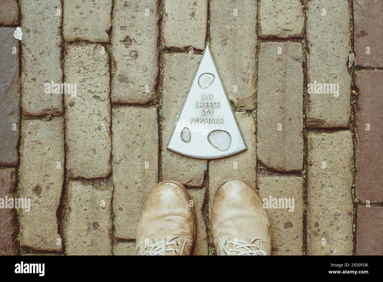 Overhead Woman's feet standing on cobbled street with a metal sign ...